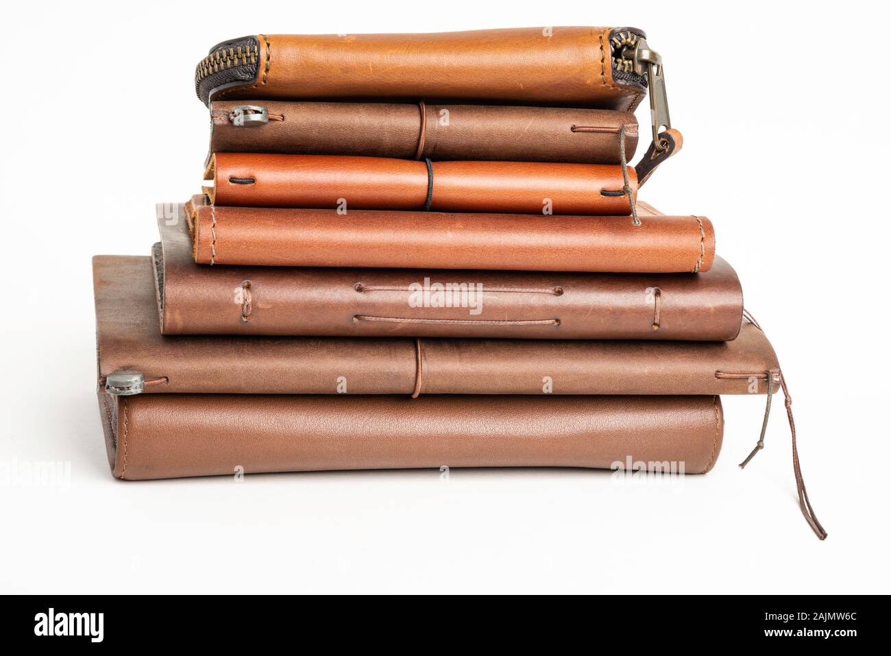 A stack of leather-bound journals, notebooks, cases, and wallets set on ...