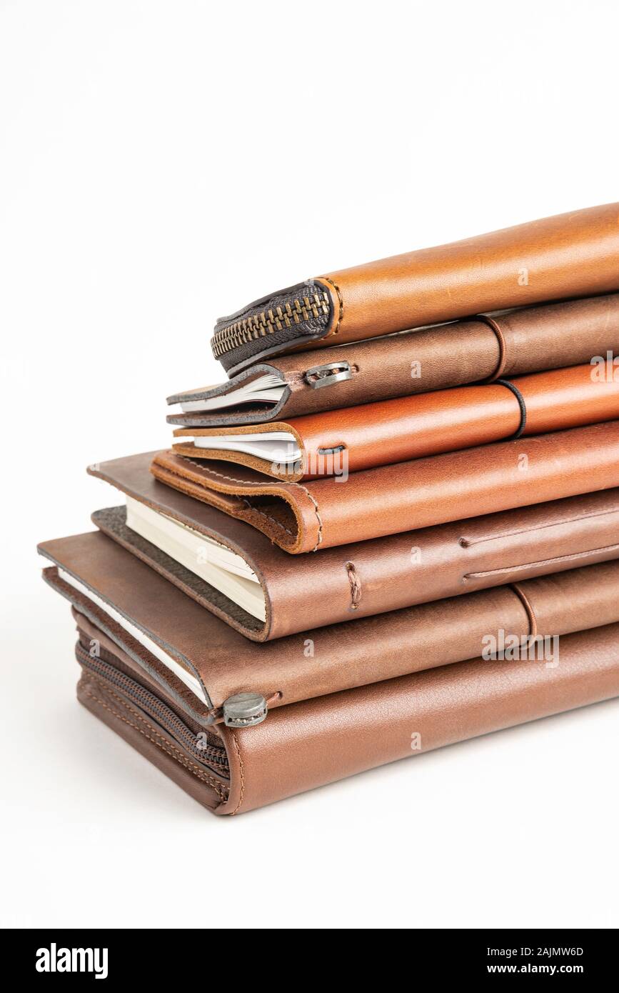 A stack of leather-bound journals, notebooks, cases, and wallets set on ...