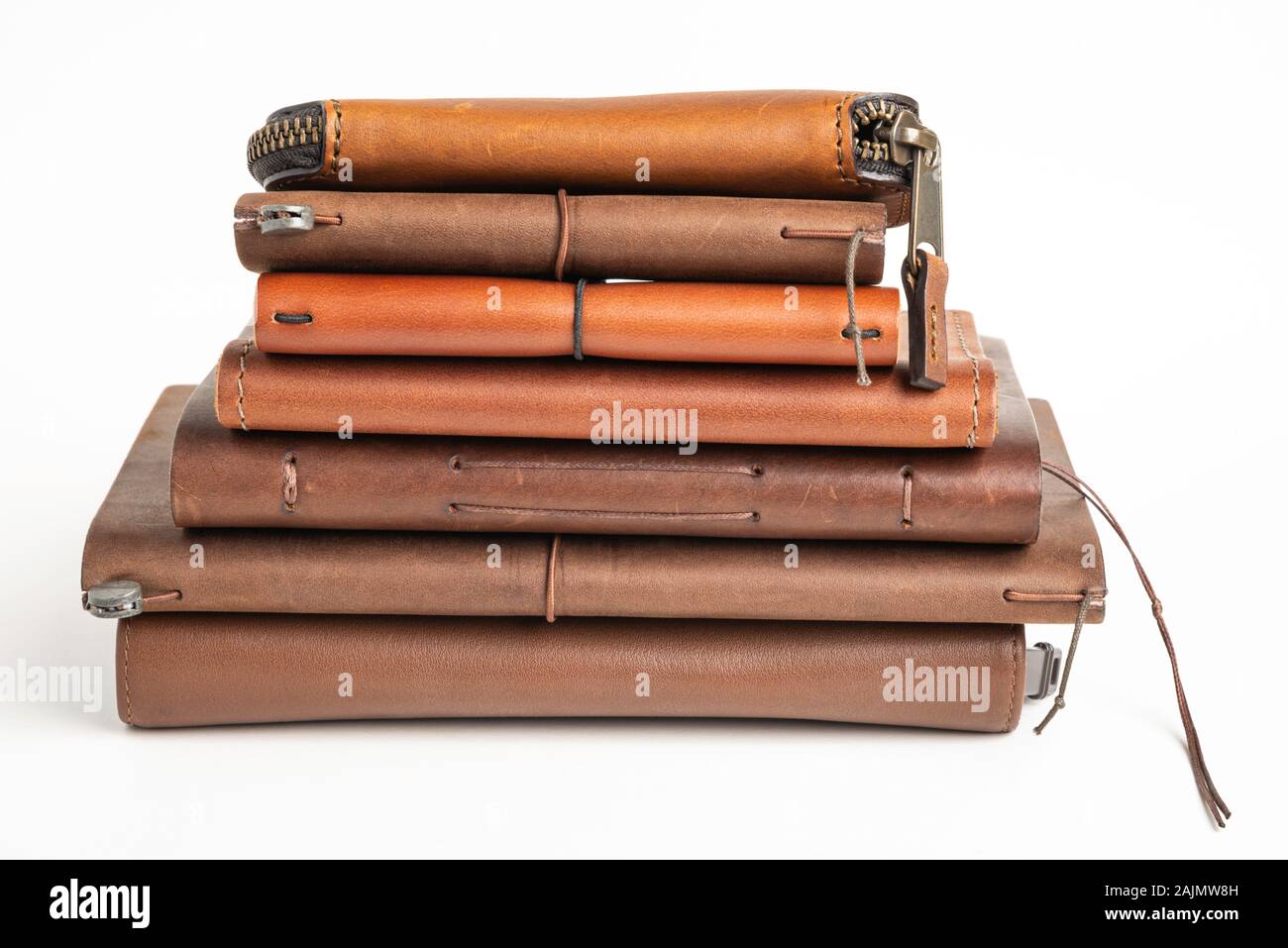 A stack of leather-bound journals, notebooks, cases, and wallets set on ...