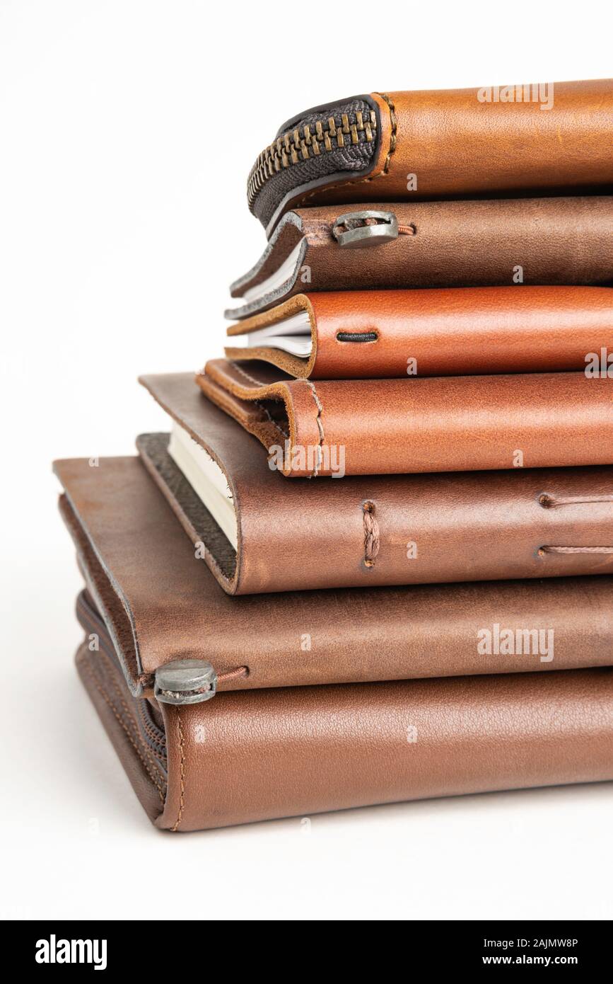 A stack of leather-bound journals, notebooks, cases, and wallets set on ...