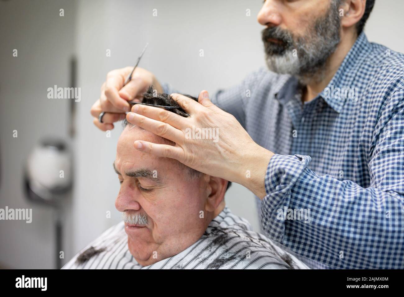 Barber trimming hair of old man at barber shop Stock Photo - Alamy