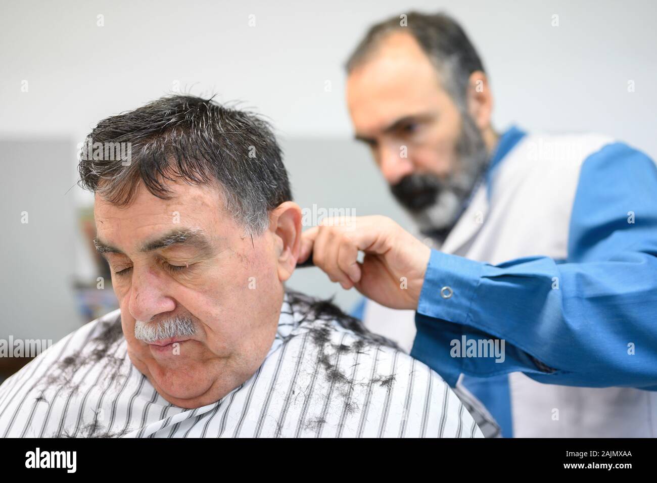 Barber trimming hair of old man at barber shop Stock Photo - Alamy