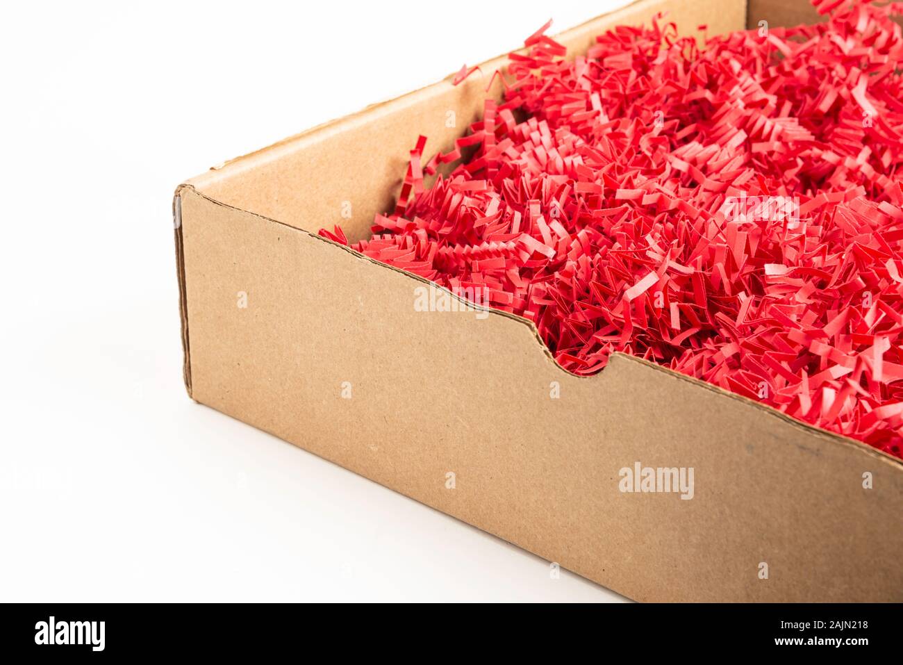 A brown cardboard package box filled with cut and crimped red paper ...
