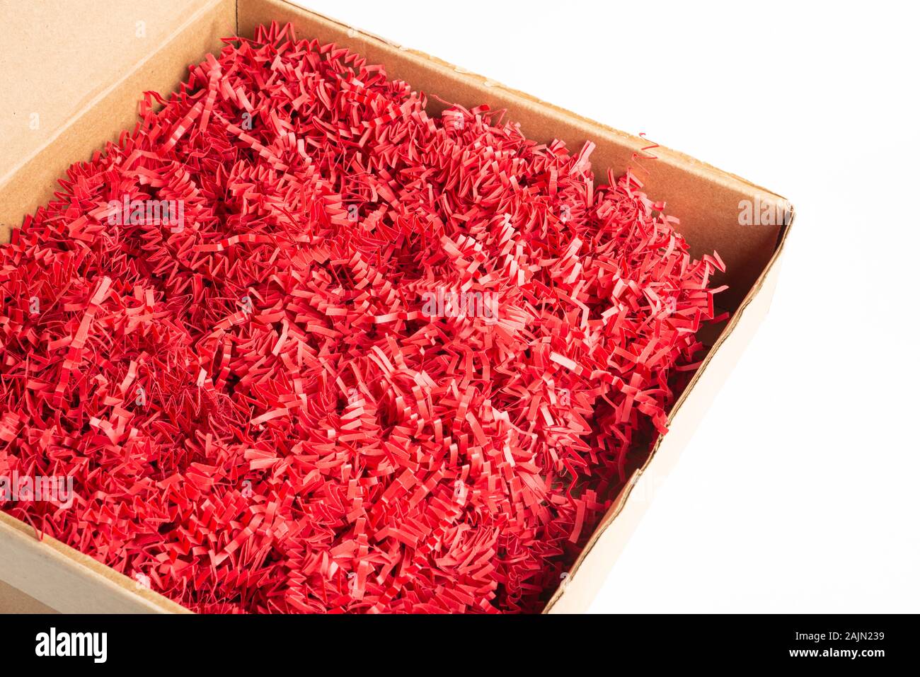 A brown cardboard package box filled with cut and crimped red paper ...