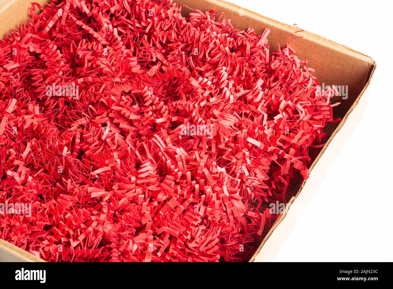 A brown cardboard package box filled with cut and crimped red paper ...