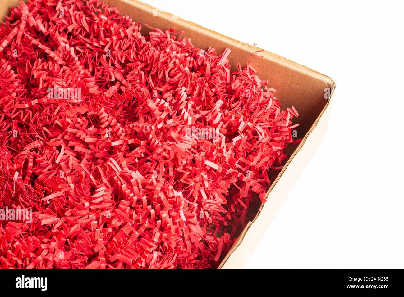 A brown cardboard package box filled with cut and crimped red paper ...