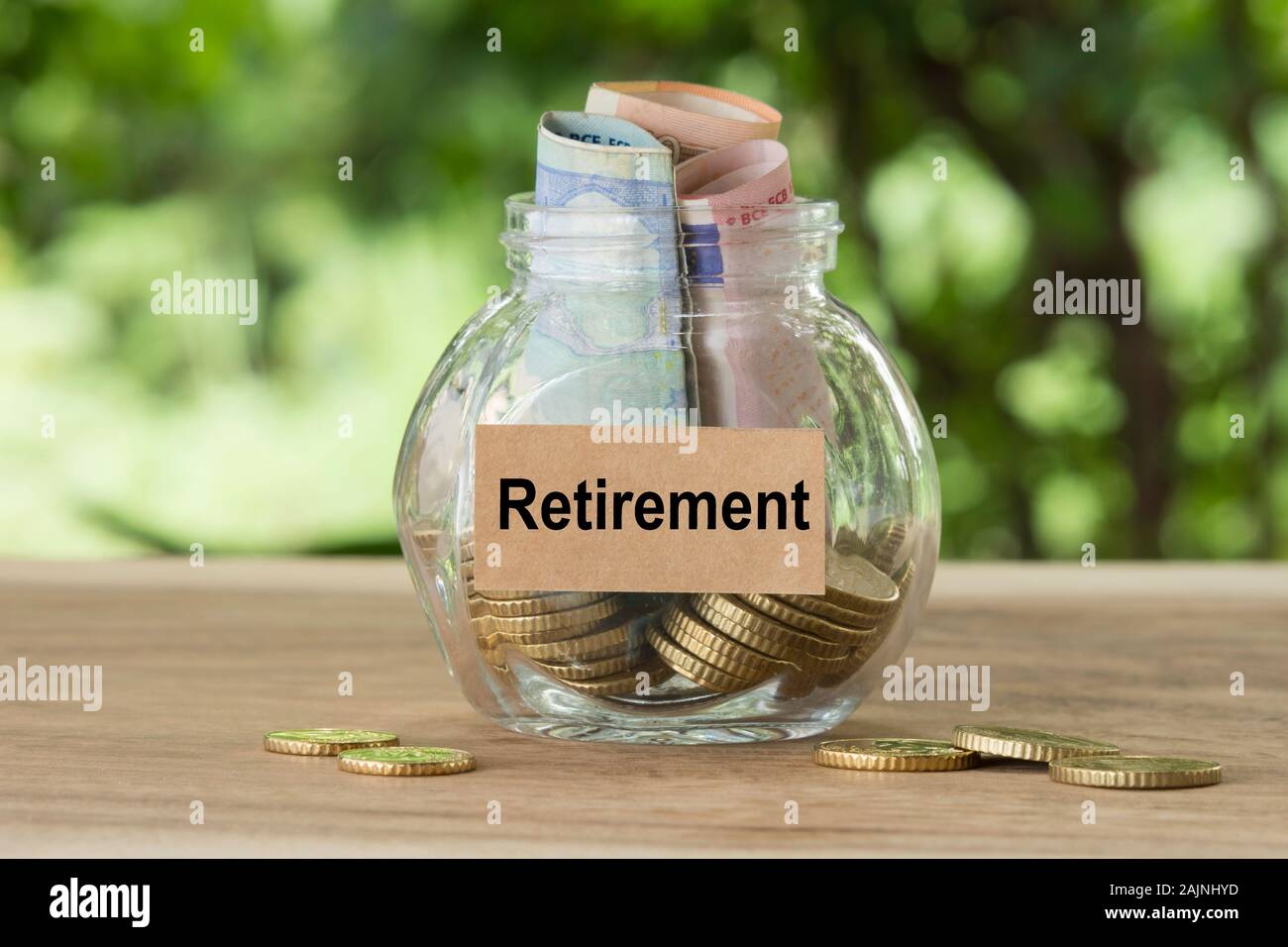 banknote and coins in glass jar with retirement label on nature ...