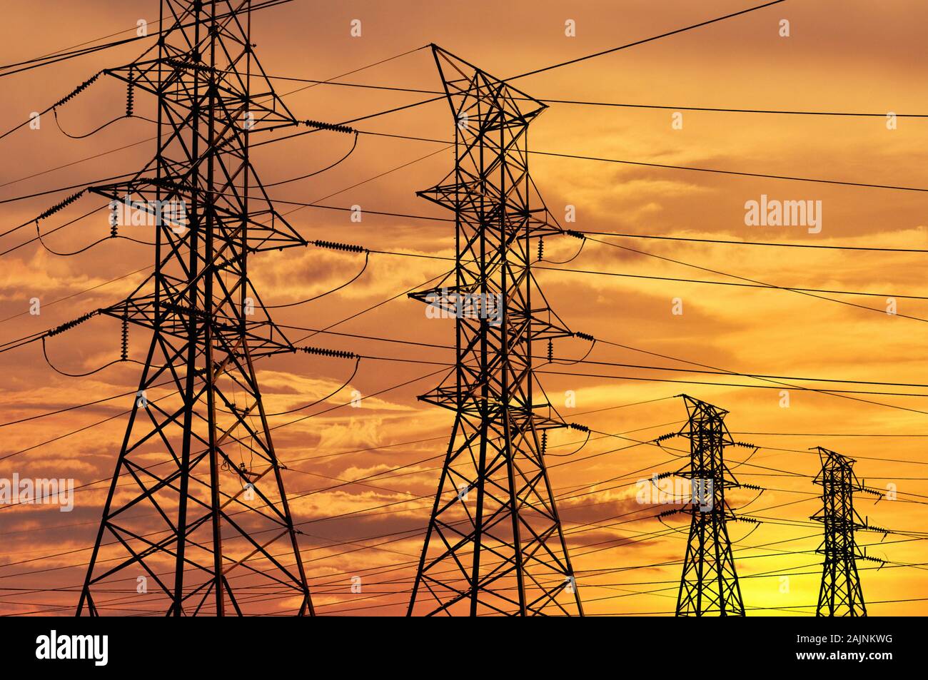 Silhouette of high voltage power line cables in an orange evening ...