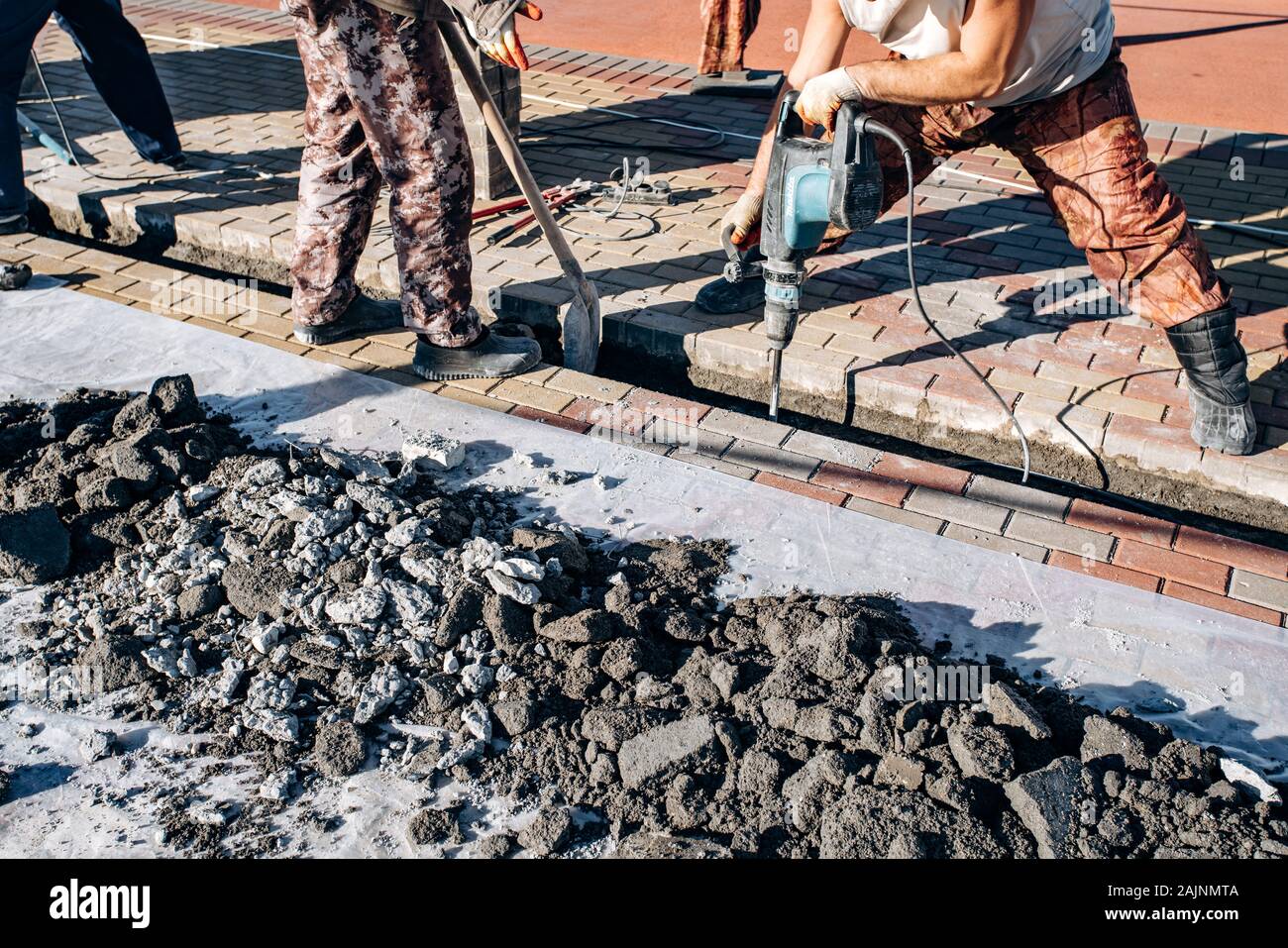 Workers laid paving slabs. Two workers lay paving slabs Stock Photo - Alamy