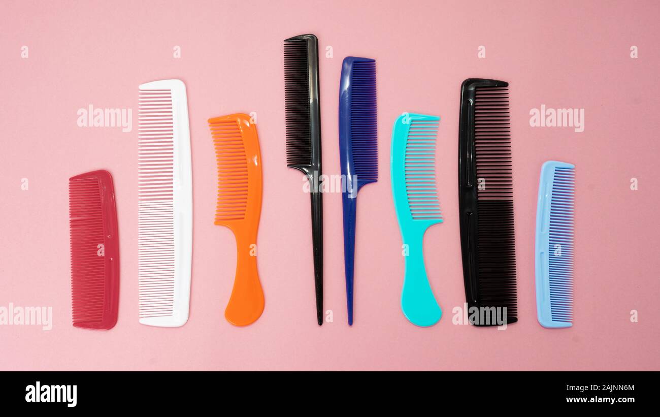 Various colored brushs and combs for hair on pink background ...
