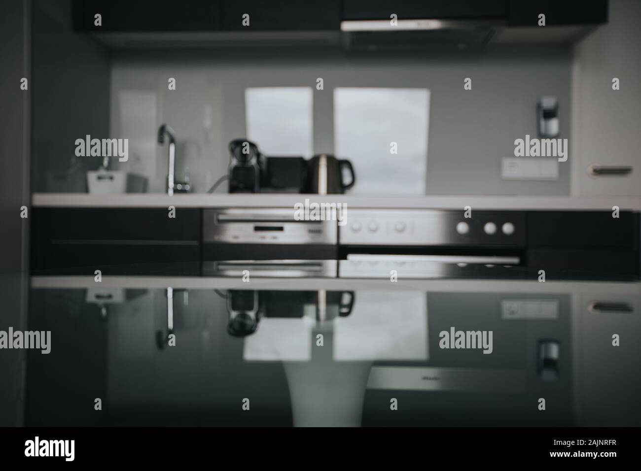 Interior of a kitchen. Focus in front on the glass table with blurred ...