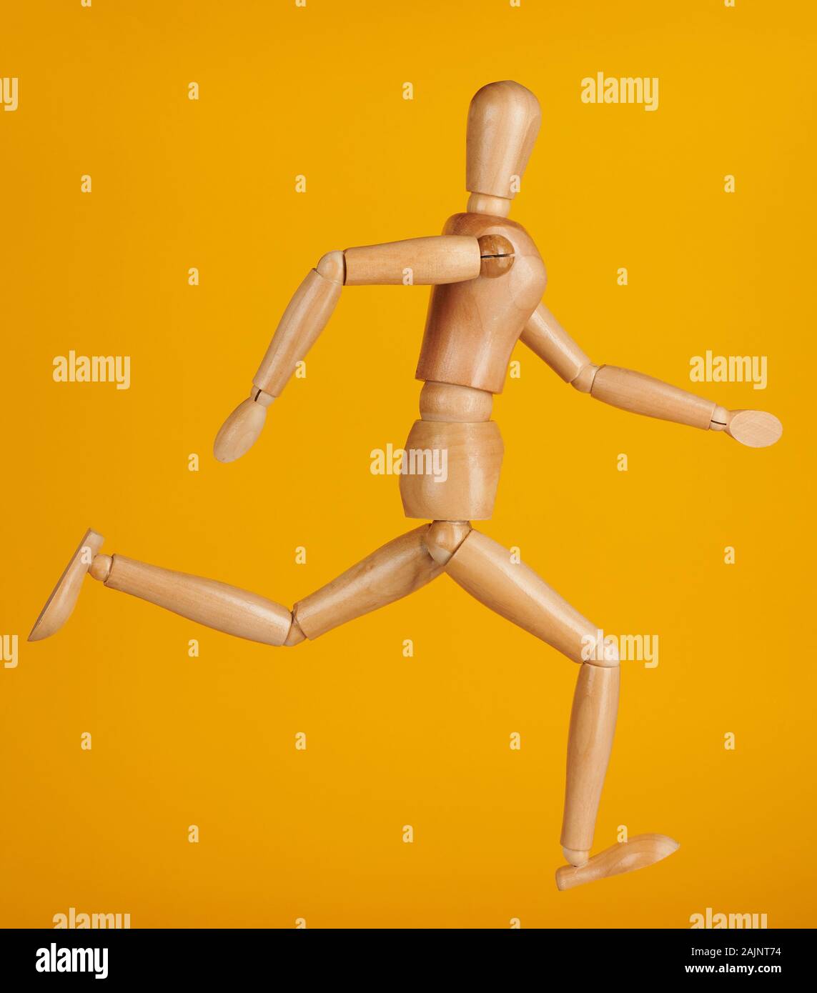 Wooden doll in run pose side view isolated on yellow background Stock ...