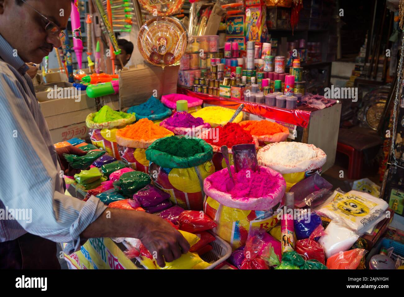 Indian Salesman in front of his shop selling colorful powder in bags ...