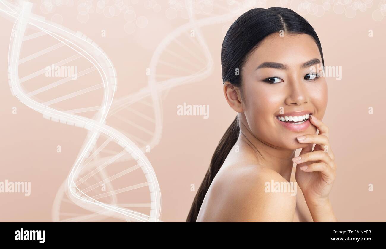 Portrait of pretty asian woman looking at white DNA chains over beige ...