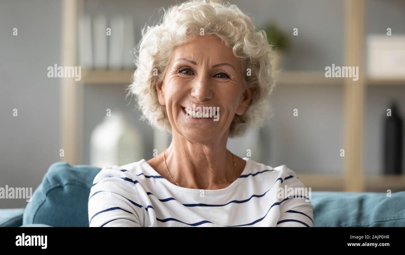 Headshot portrait elderly woman resting on couch looking at camera ...