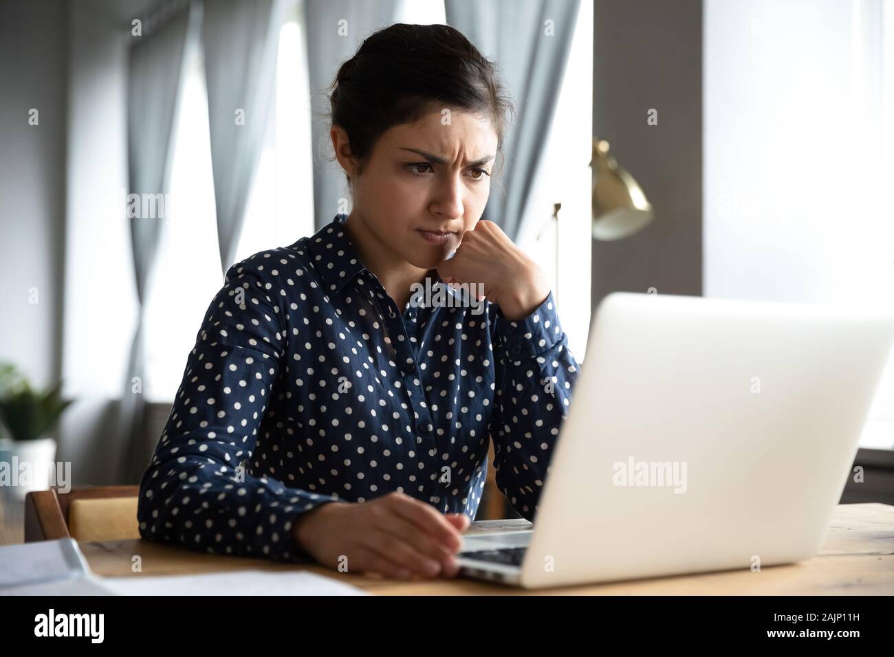 Concerned indian woman look at laptop frustrated about computer problem ...
