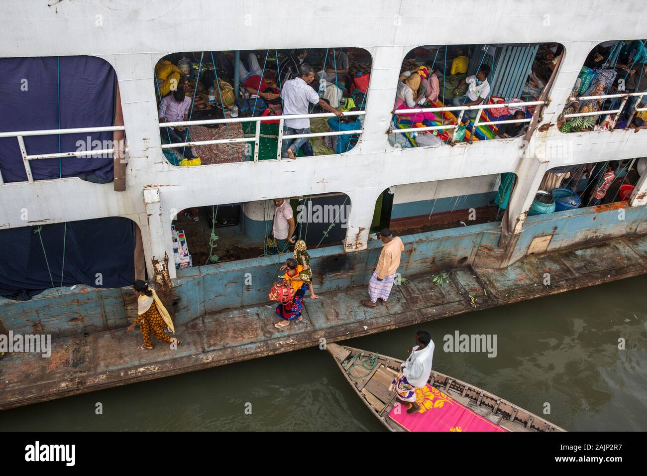 People board on a vessel using a small boat at Sadarghat Launch ...