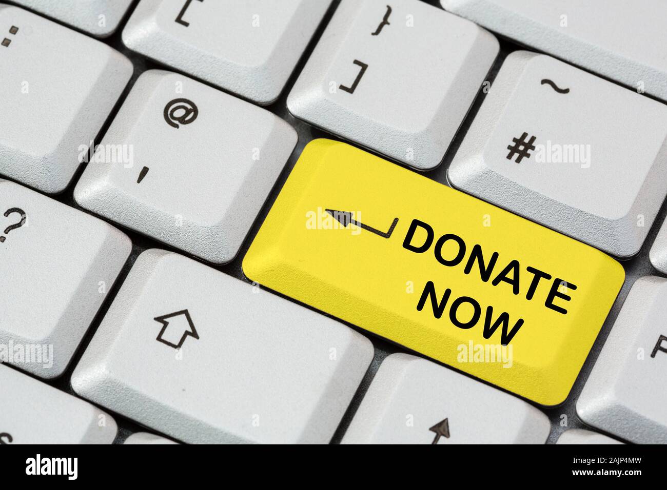 A keyboard with Donate Now written in black lettering on a yellow enter ...