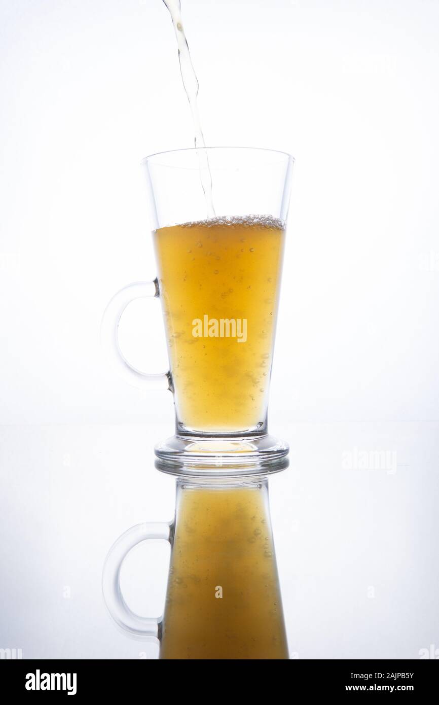 Light unfiltered beer poured into a steaming mug on a white background ...