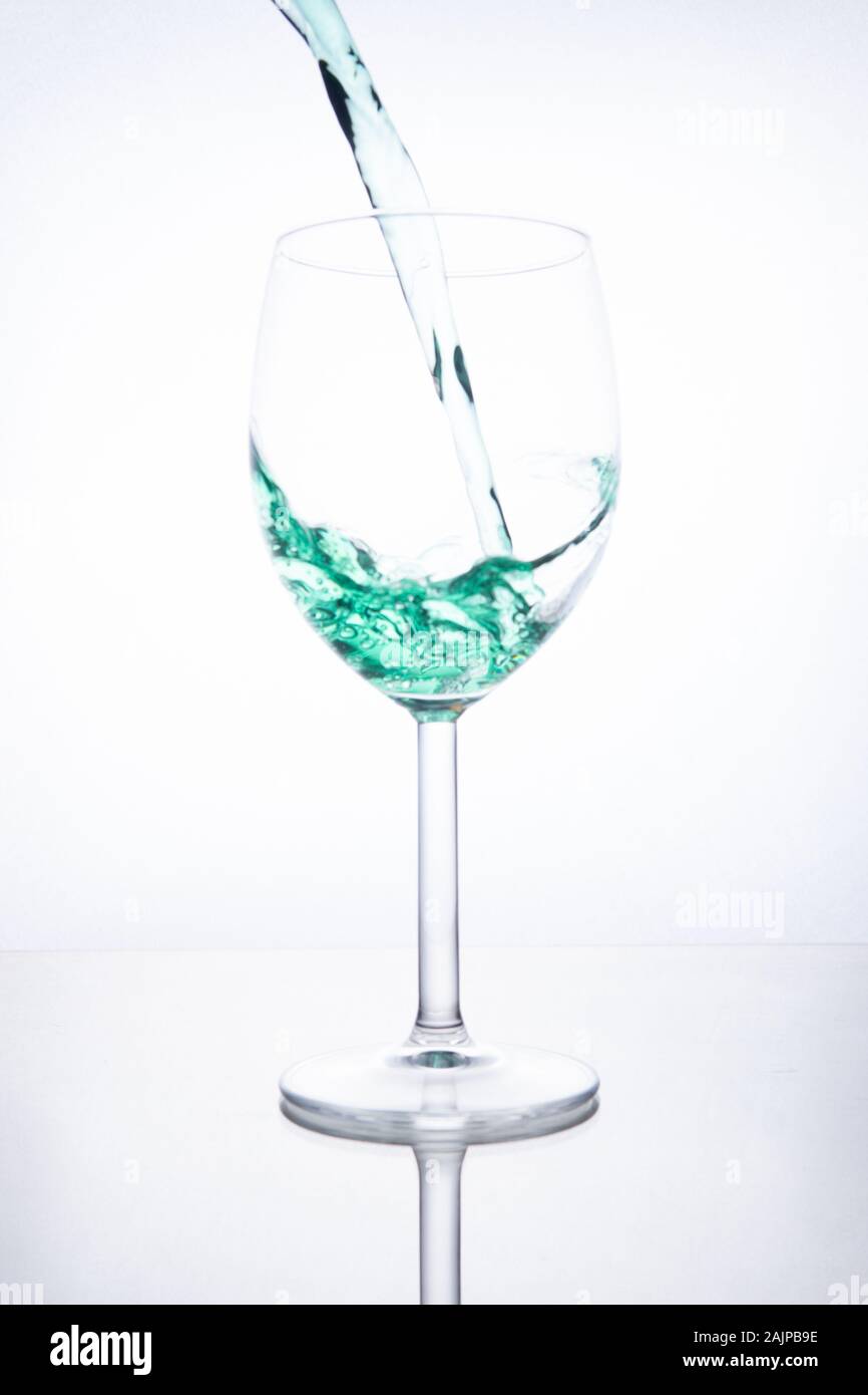 Green cocktail is poured into a glass on a white background with ...