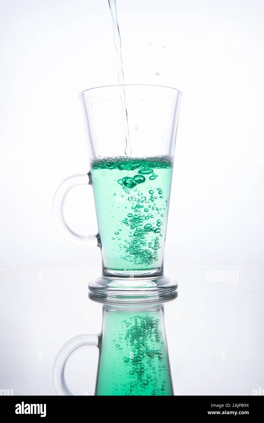 Green cocktail is poured into a glass on a white background with ...