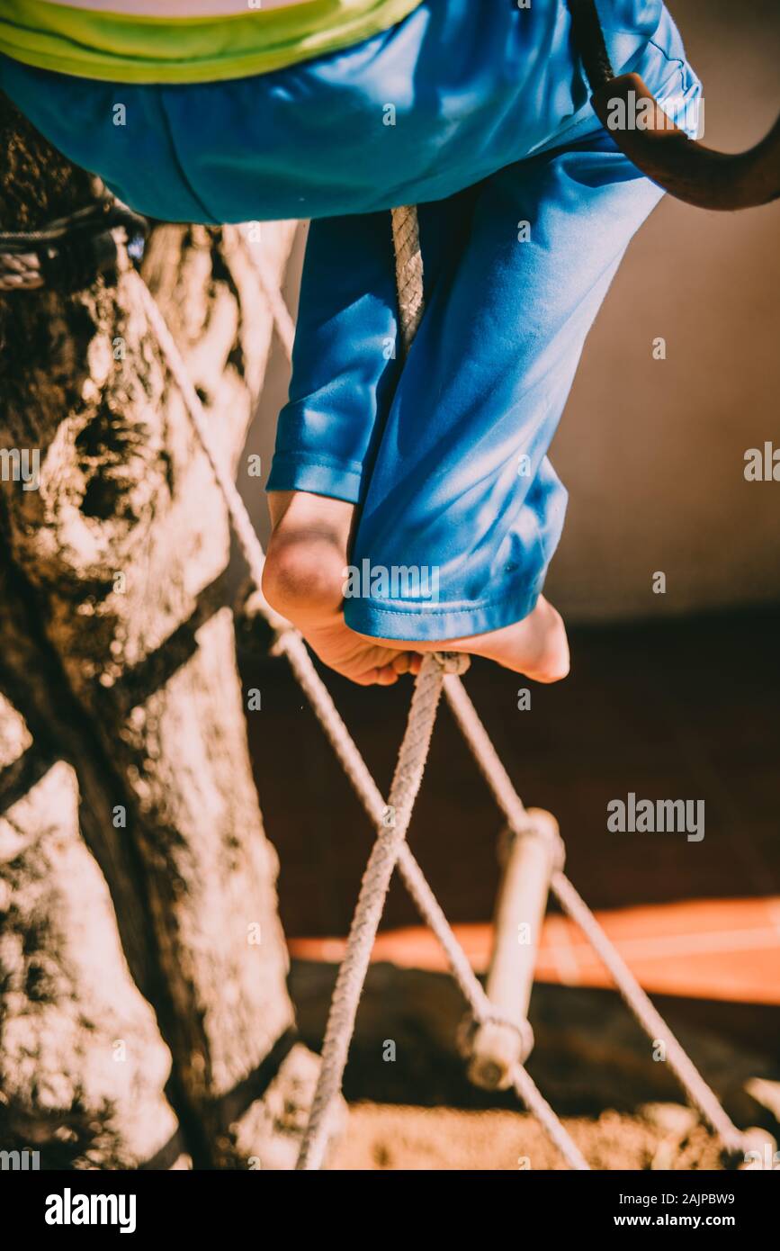 Bare feet of a boy holding on to a rope while climbing up it Stock ...