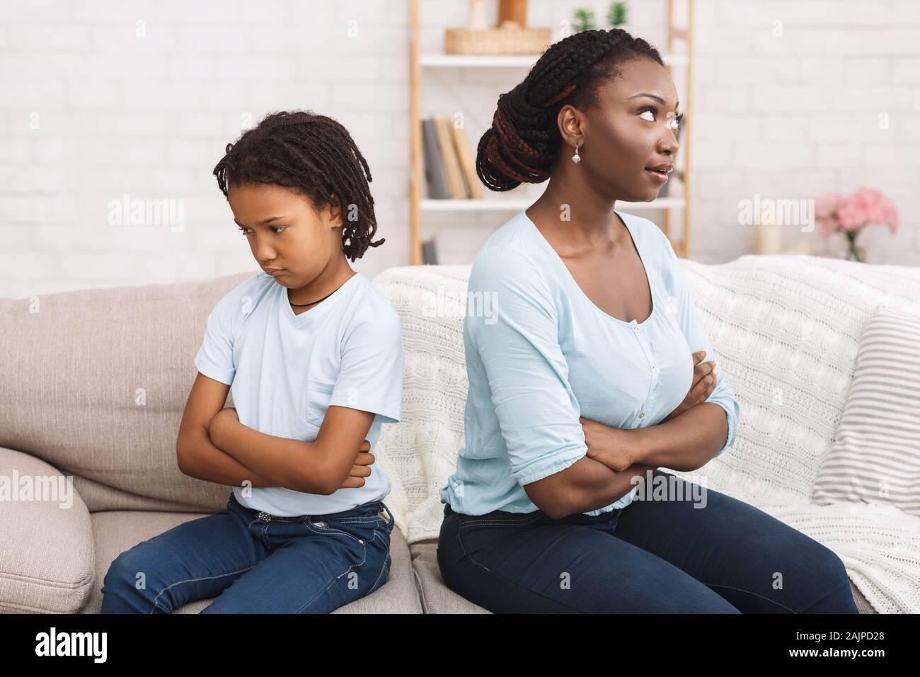 Family Disagreement. Angry black mother and daughter sitting back to back on sofa at home after ...
