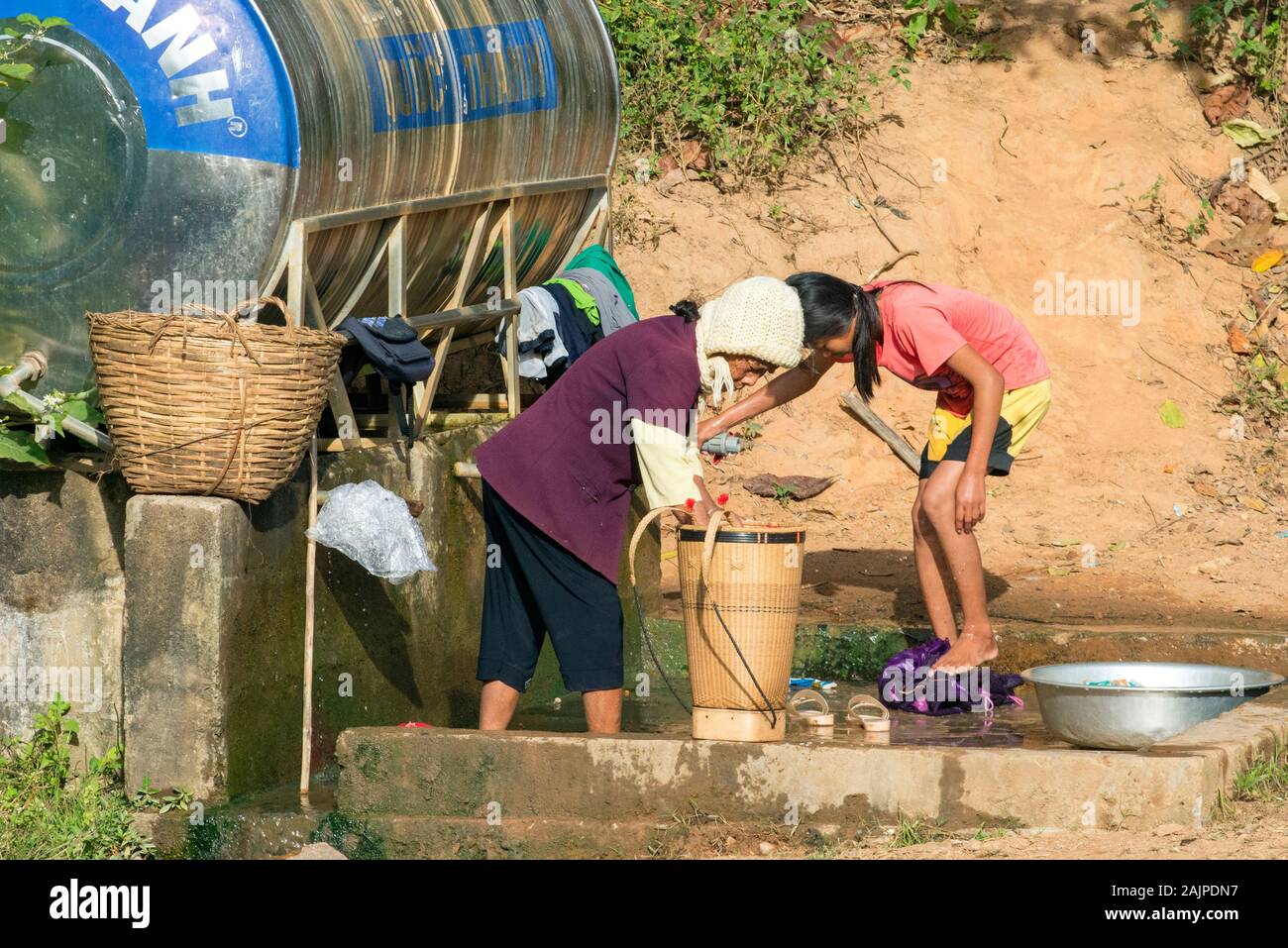 TWO WOMEN WASHING CLOTHES NEXT TO A WATER TANK Stock Photo - Alamy