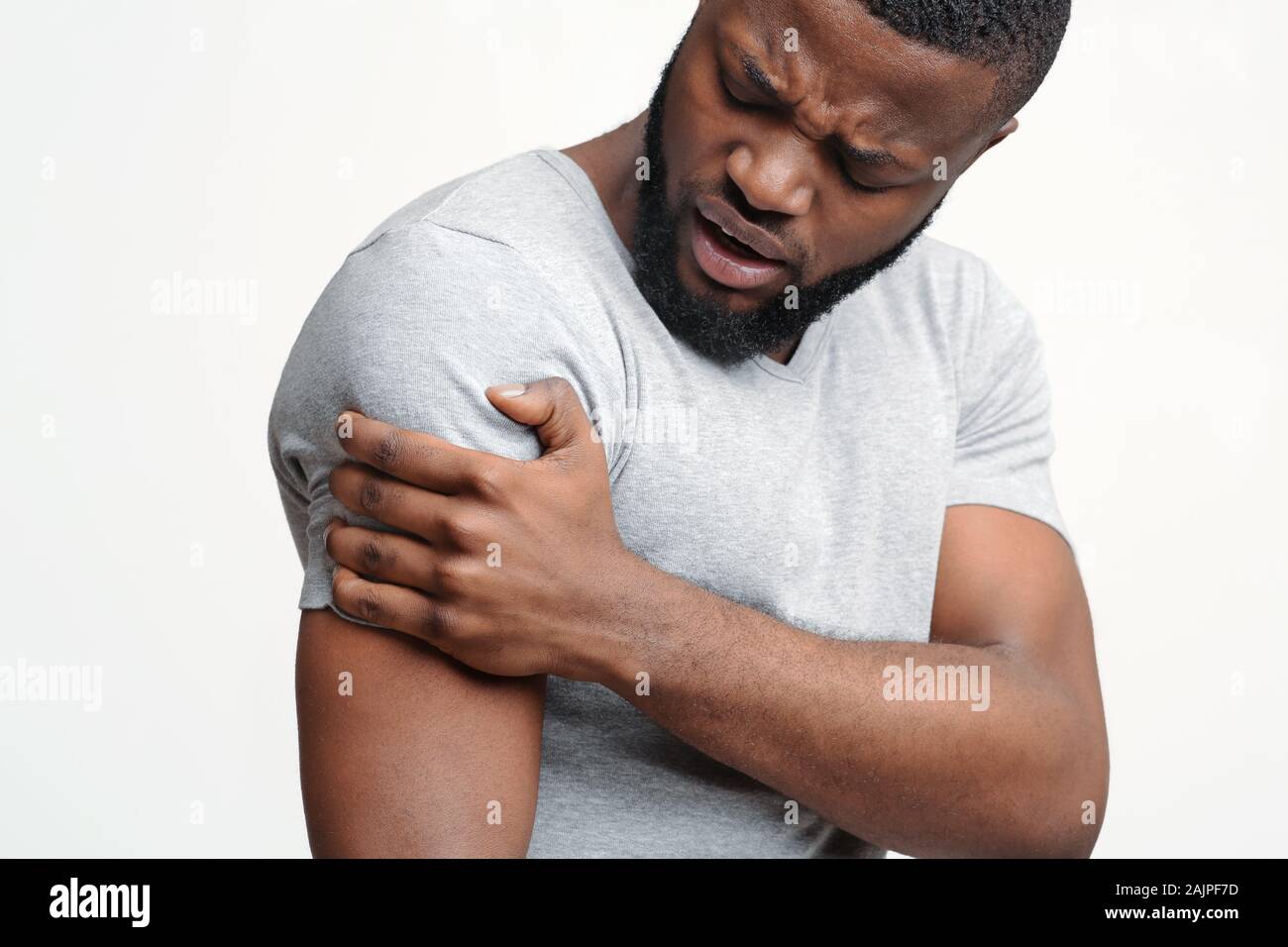 Young afro guy rubbing his itching forearm over white background ...