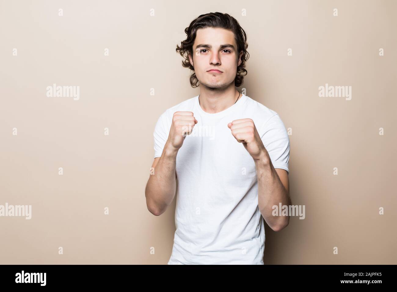 Young handsome man angry raising fist on beige background Stock Photo ...