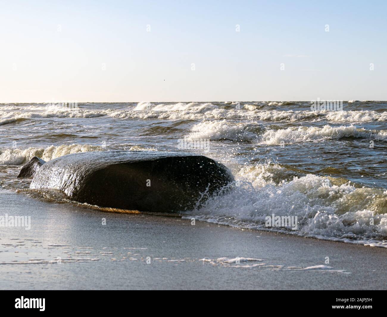 backlit landscape with stony sea shore, dark rocky silhouettes of sea ...