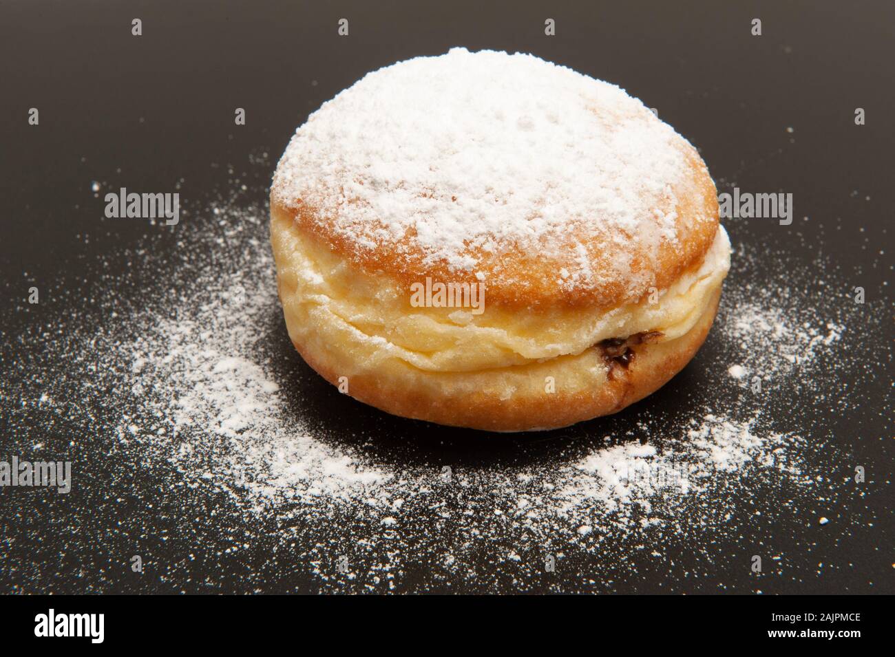 donut in icing sugar on a black background Stock Photo - Alamy