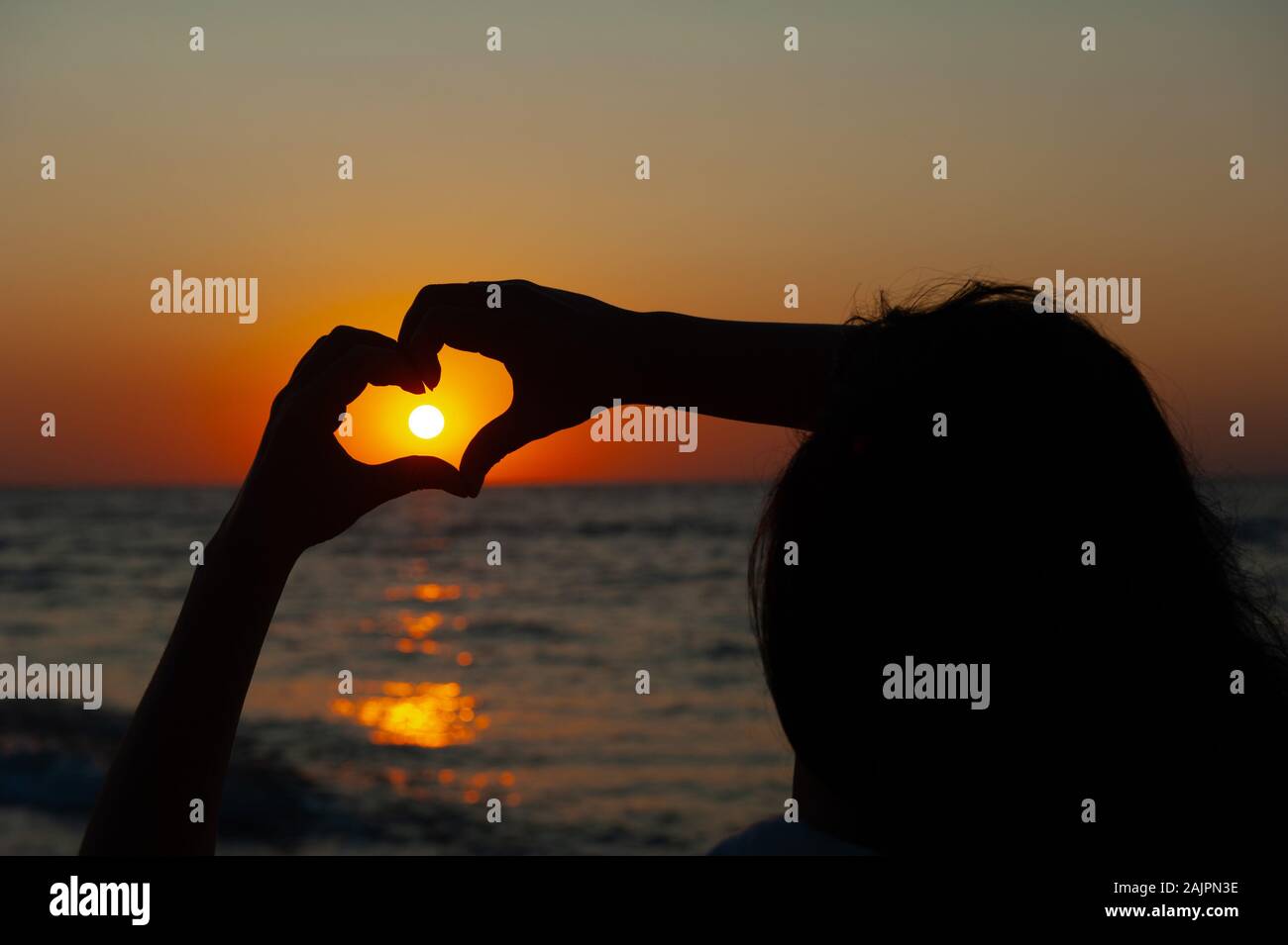 heart Sign with hands against the sunset, sunrise on the sea Stock ...