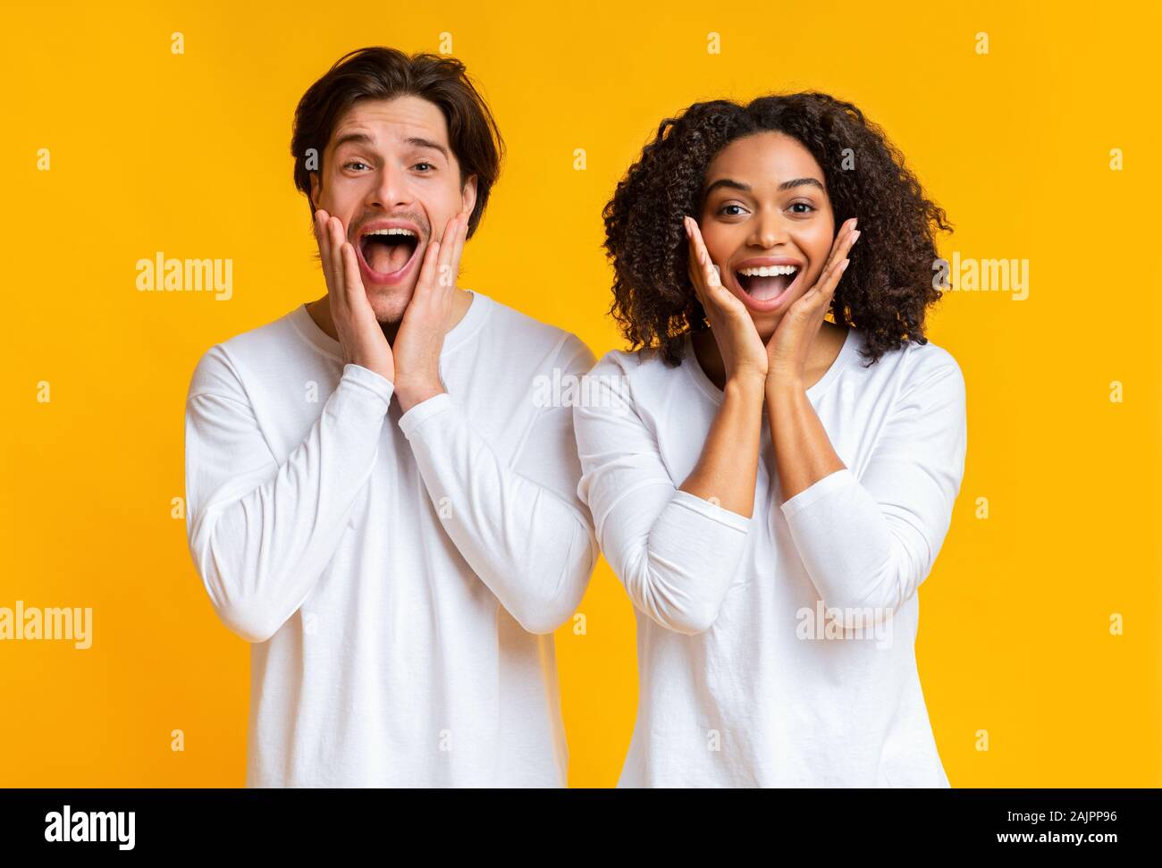 Wow. Excited multiracial couple opening mouths and touching cheeks in ...