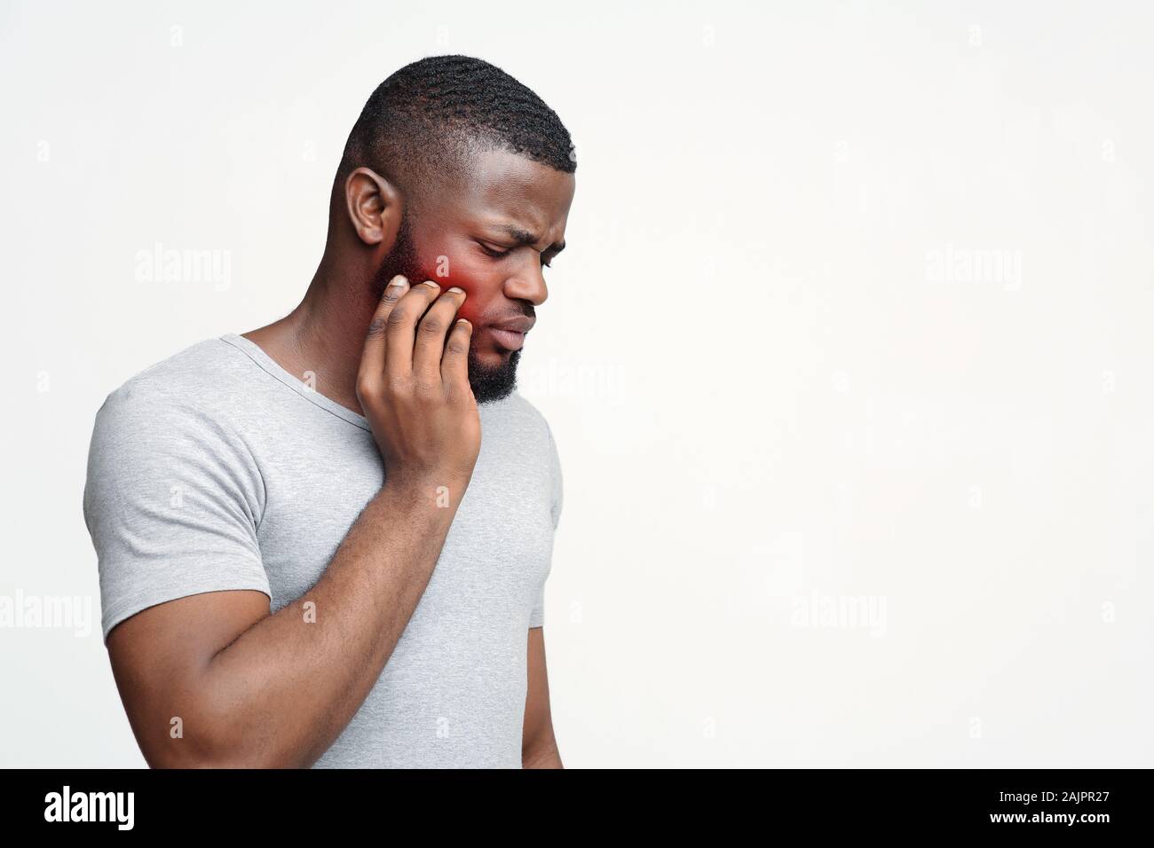Upset black guy suffering from strong pulpitis, white studio background ...