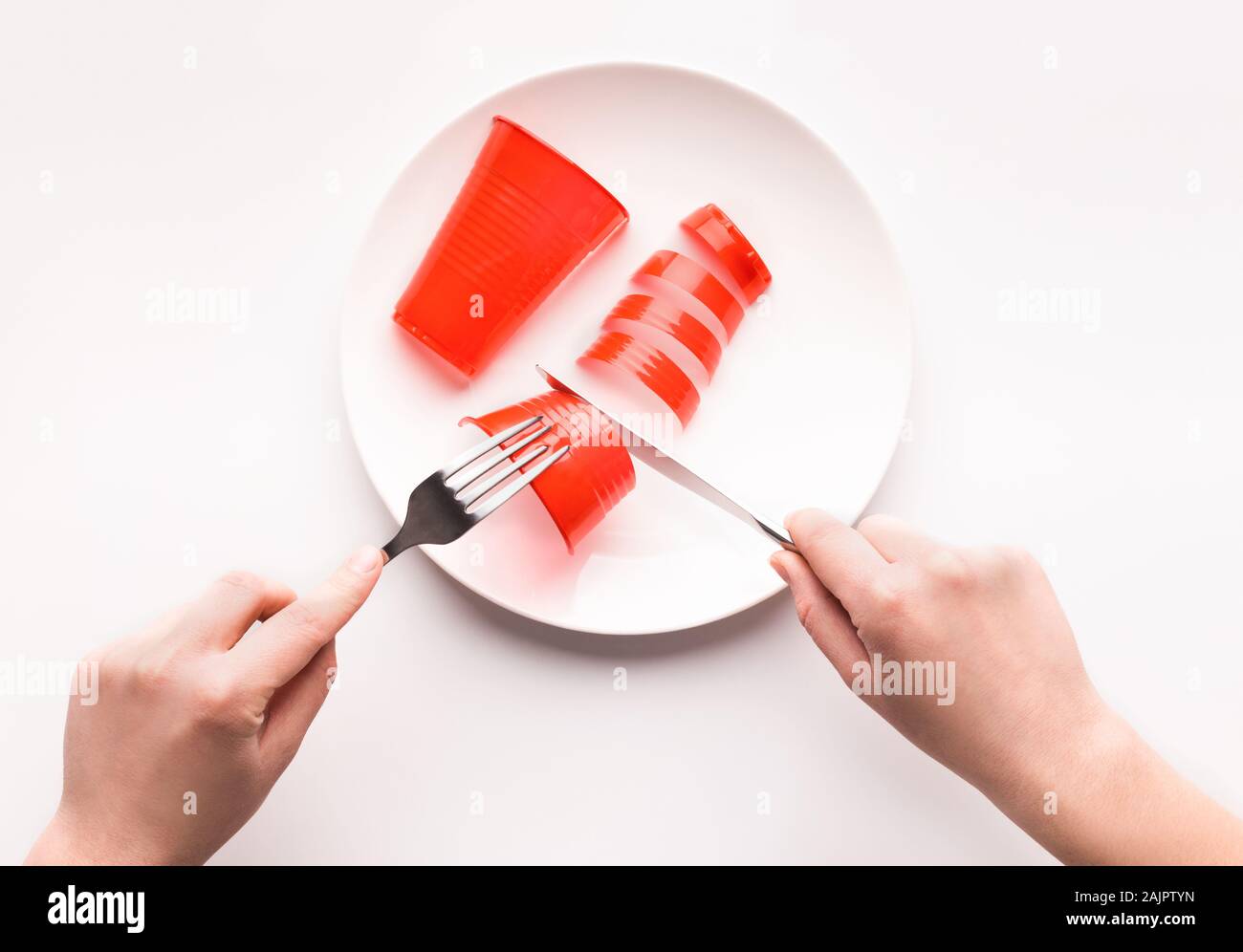 Microplastic in food. Man eating sausage of red plastic from plate ...