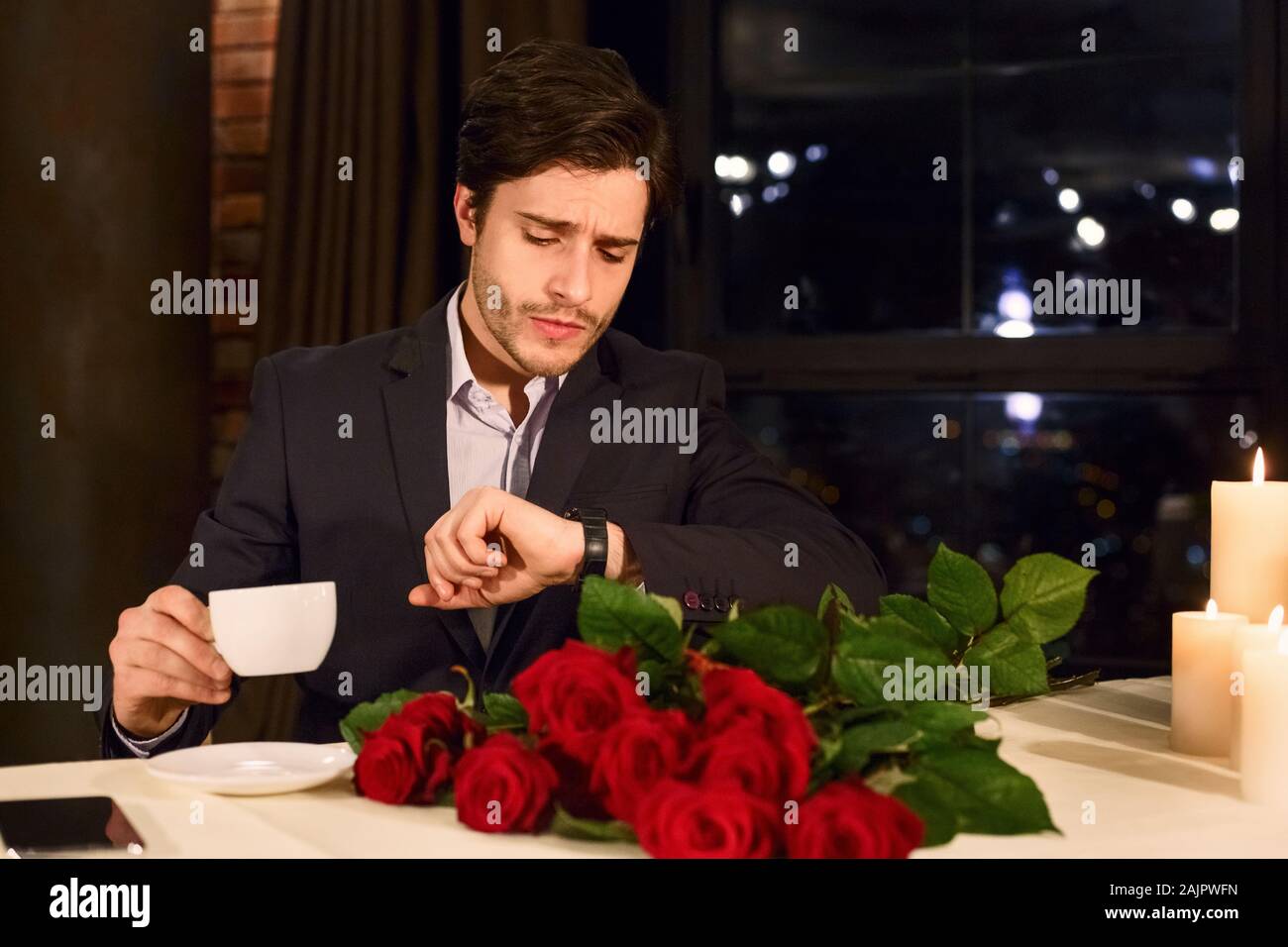Man with flowers waiting girlfriend in restaurant nervous, drinking ...