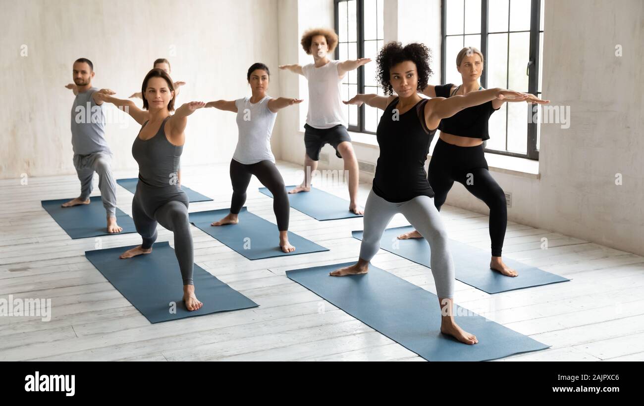 Diverse people practicing yoga at group lesson, Warrior two pose Stock ...