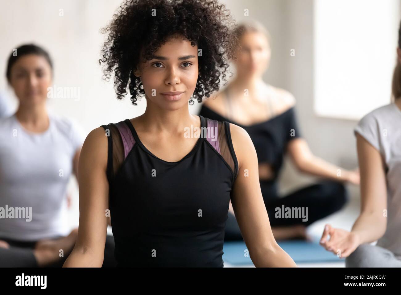 African American woman practicing yoga at group lesson, Padmasana ...