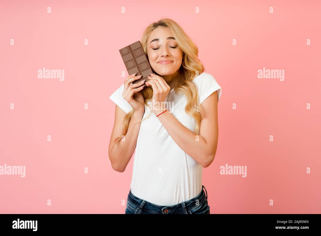 Pretty millennial woman hugging chocolate bar, want to eat sweets, pink ...