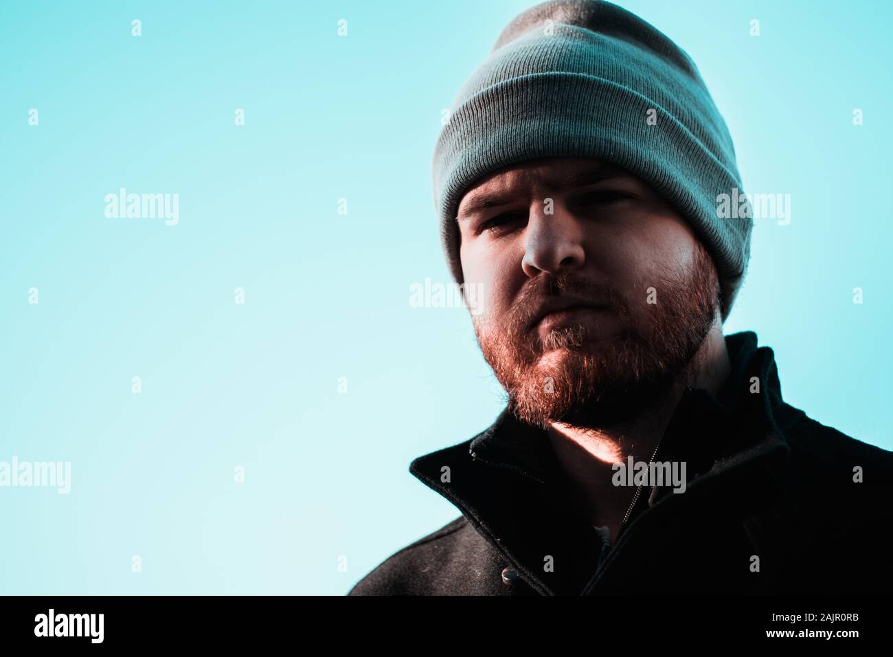 Bearded man with a beanie looking at the camera with a serious look ...