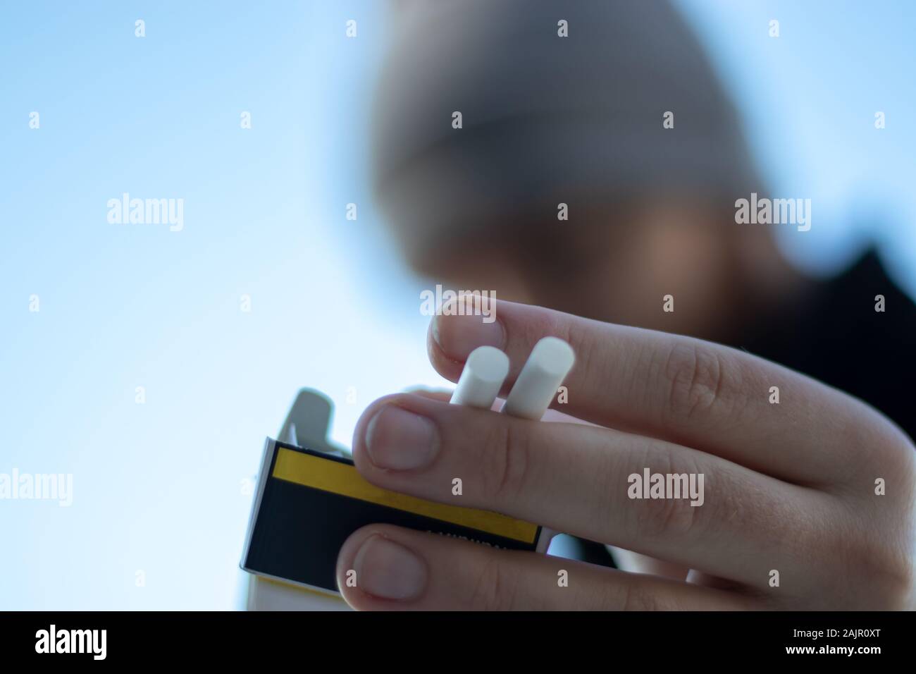 Male hand offering a pack of cigarettes, two cigarettes poking out of ...