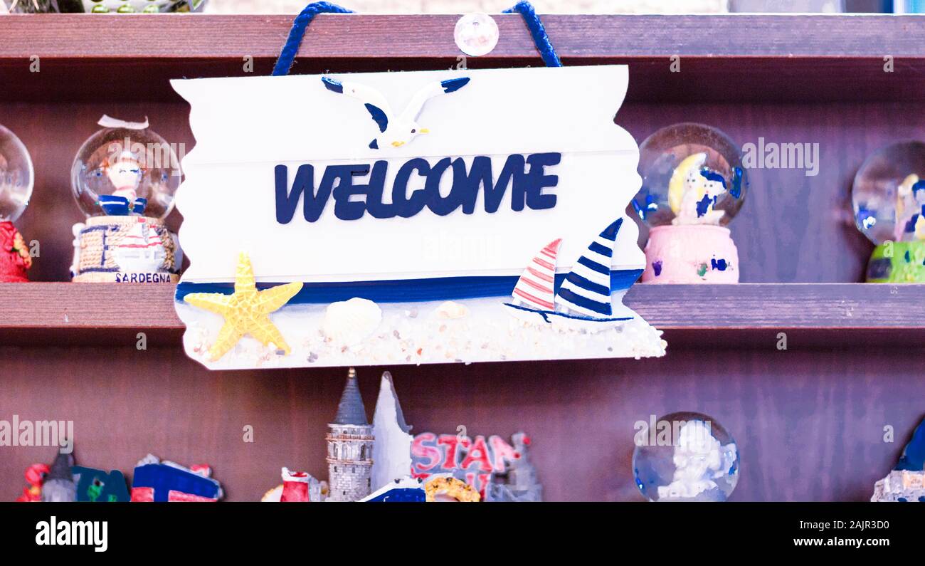 Welcome sign written on the signboard hanging in front of the shelf ...