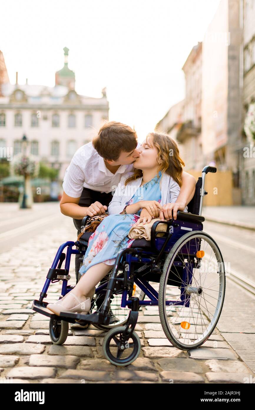 Walk in the city. Cheerful wheelchair girl kissing with her handsome ...