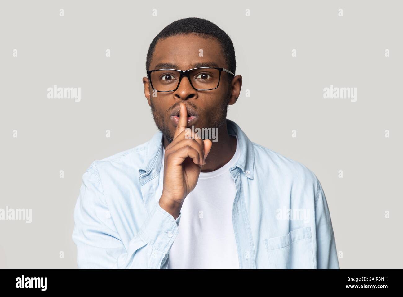 African man put finger on lips makes hush gesture Stock Photo - Alamy