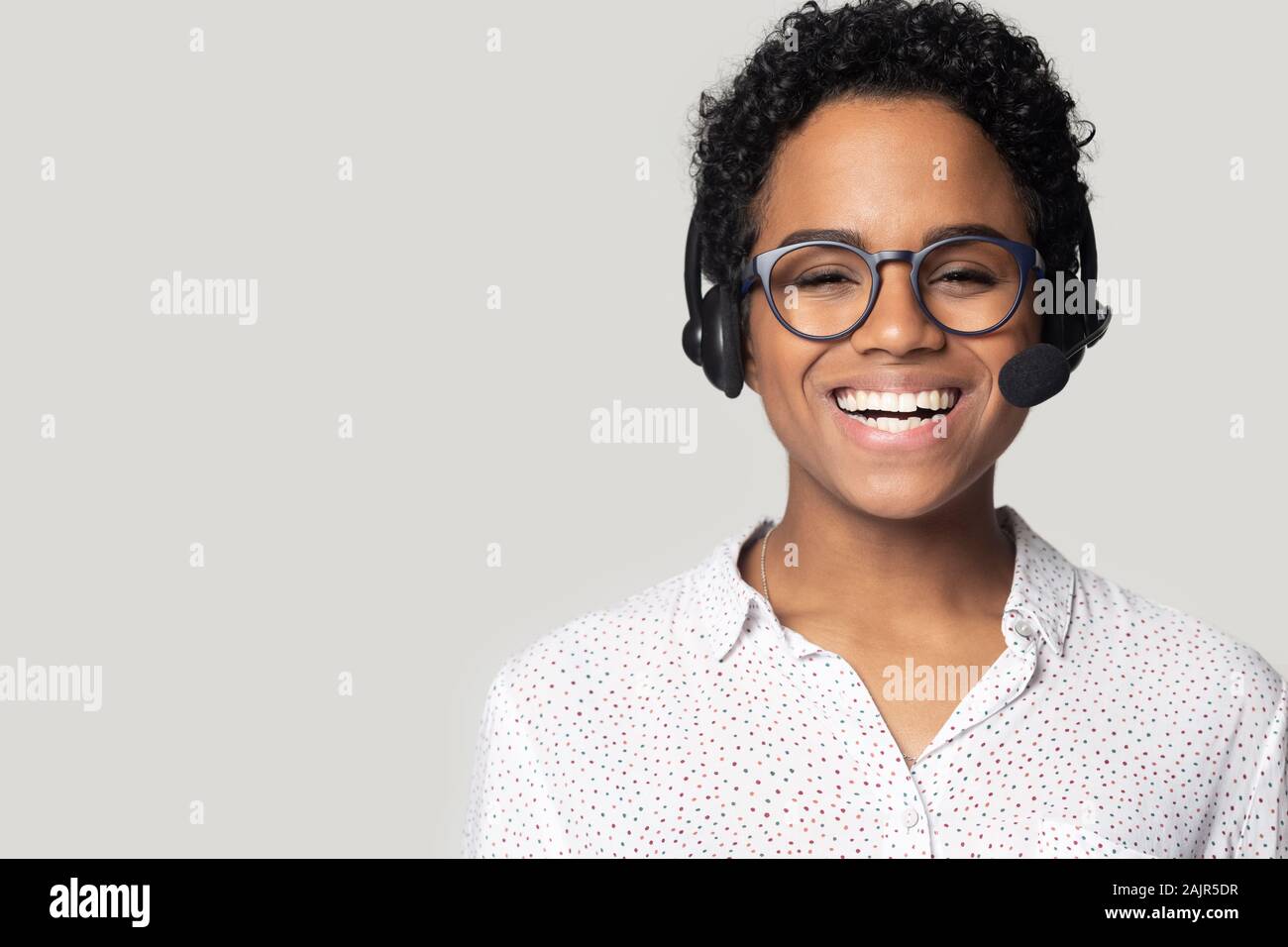 African woman wearing headset with microphone posing isolated on grey ...