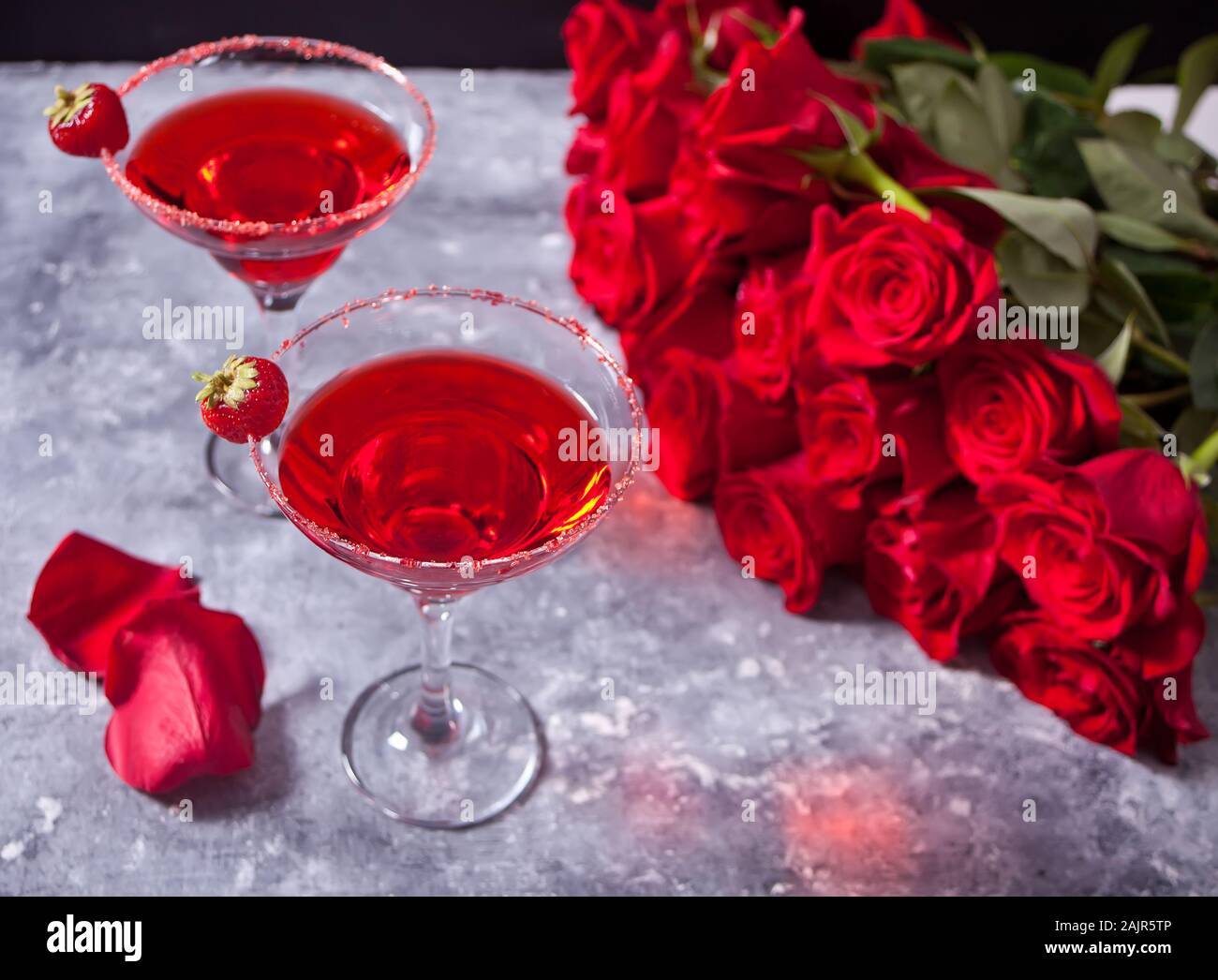 Red fresh exotic alcoholic cocktail in clear glass and red roses for ...