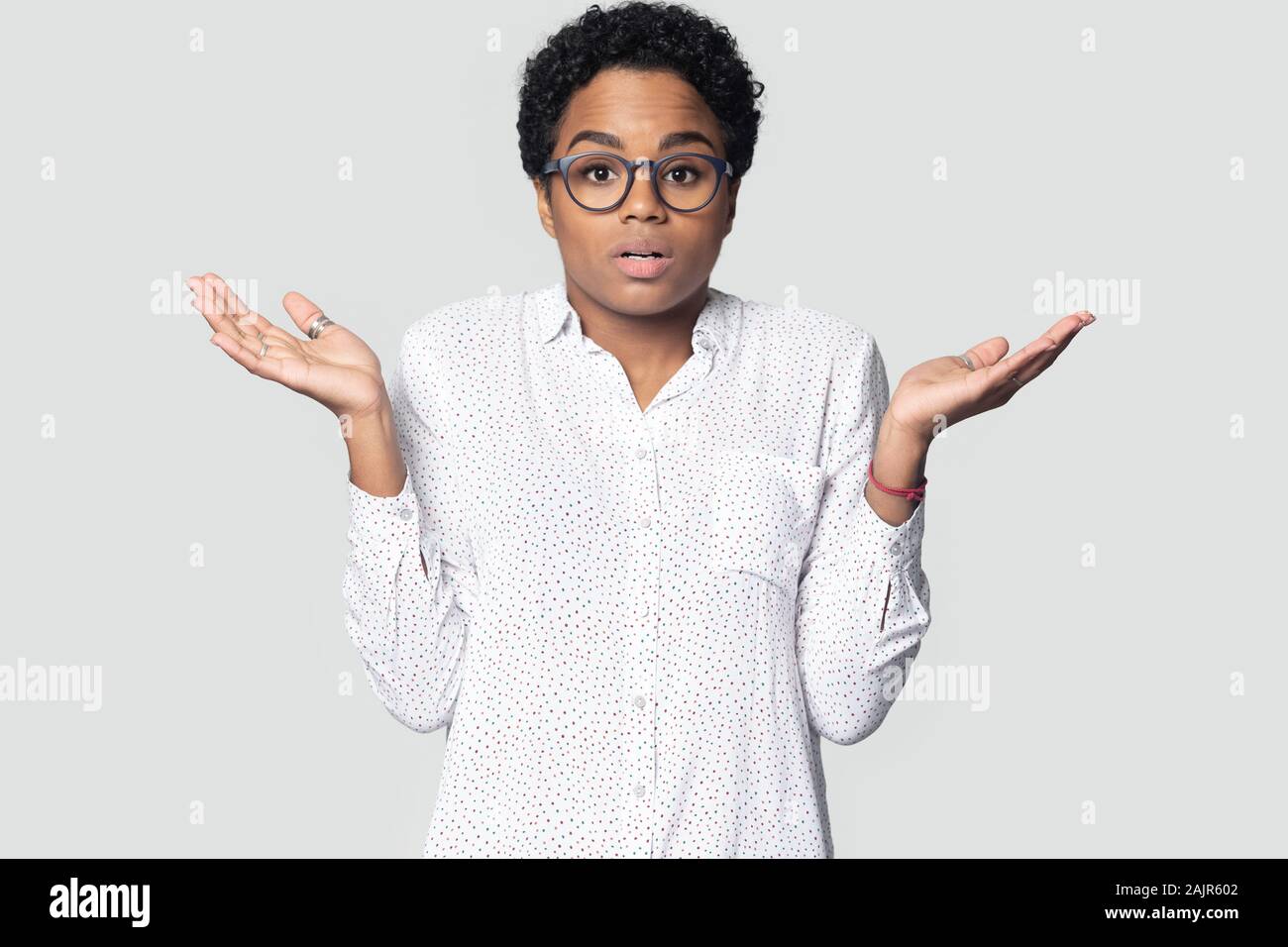 Confused african woman shrugged her shoulders raised palms studio shot ...