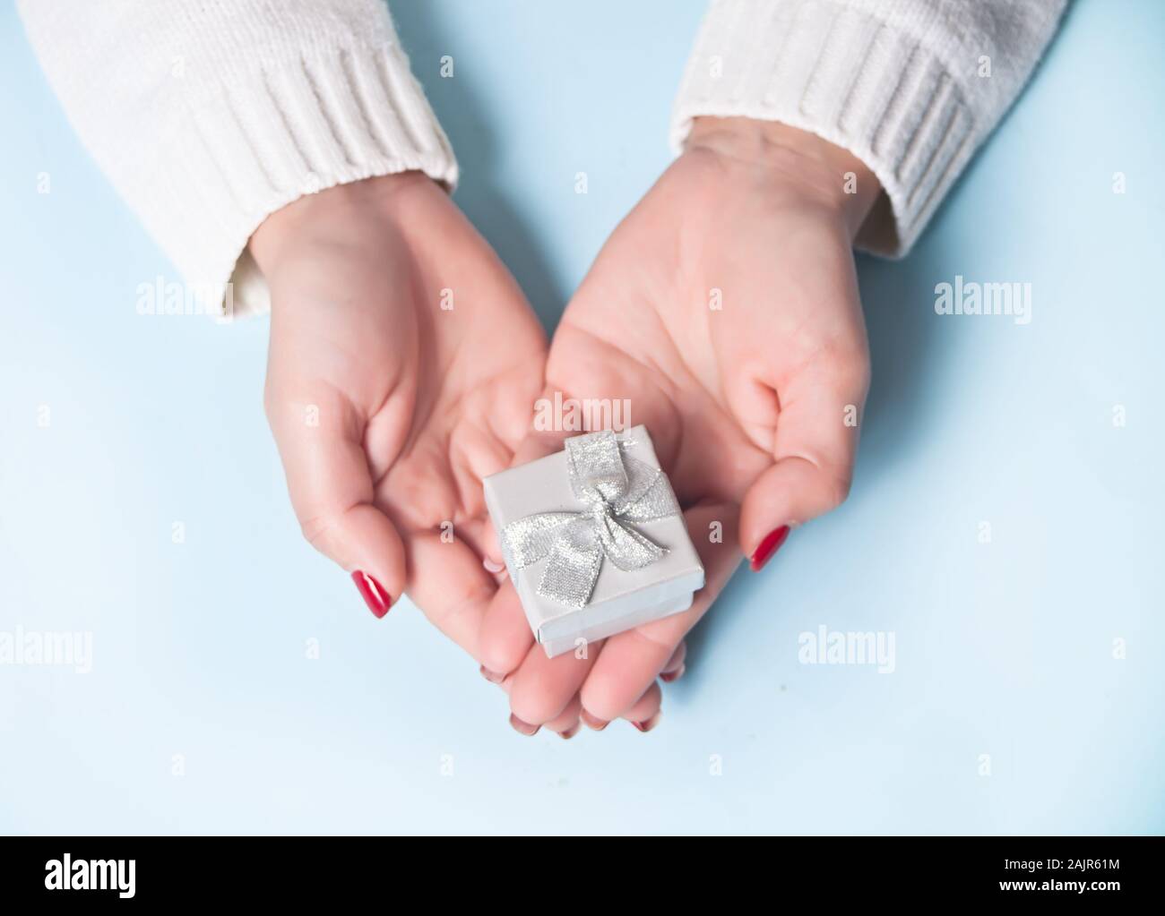 Woman holding a small goft box in a hands on the blue background ...