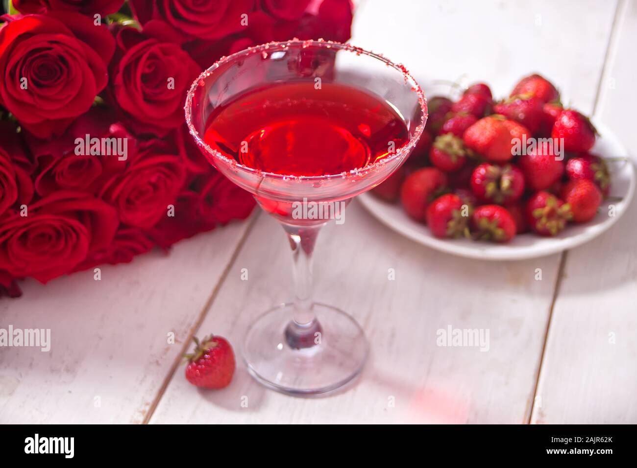 Red exotic alcoholic cocktail in clear glass, plate with fresh ...